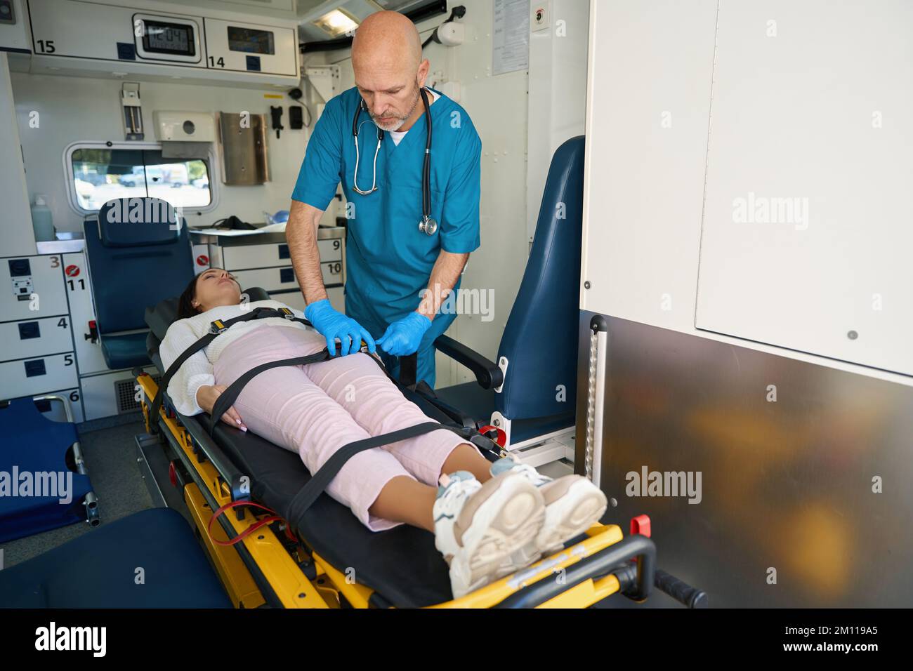 Doctor tightens seat belts on body of patient in ambulance Stock Photo ...