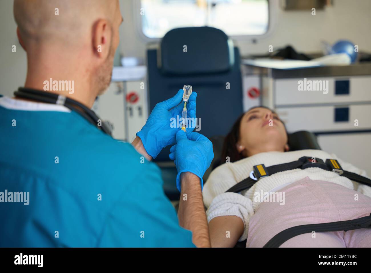 Doctor preparing syringe for injection to woman on a gurney Stock Photo ...