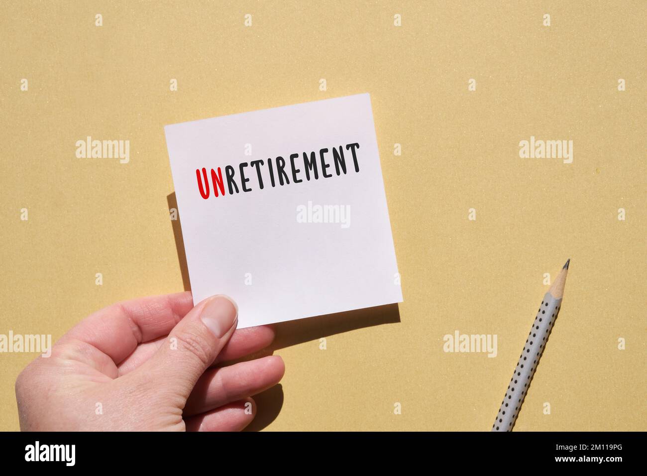 Unretirement word written on square paper note in hand. Top view, flat ...