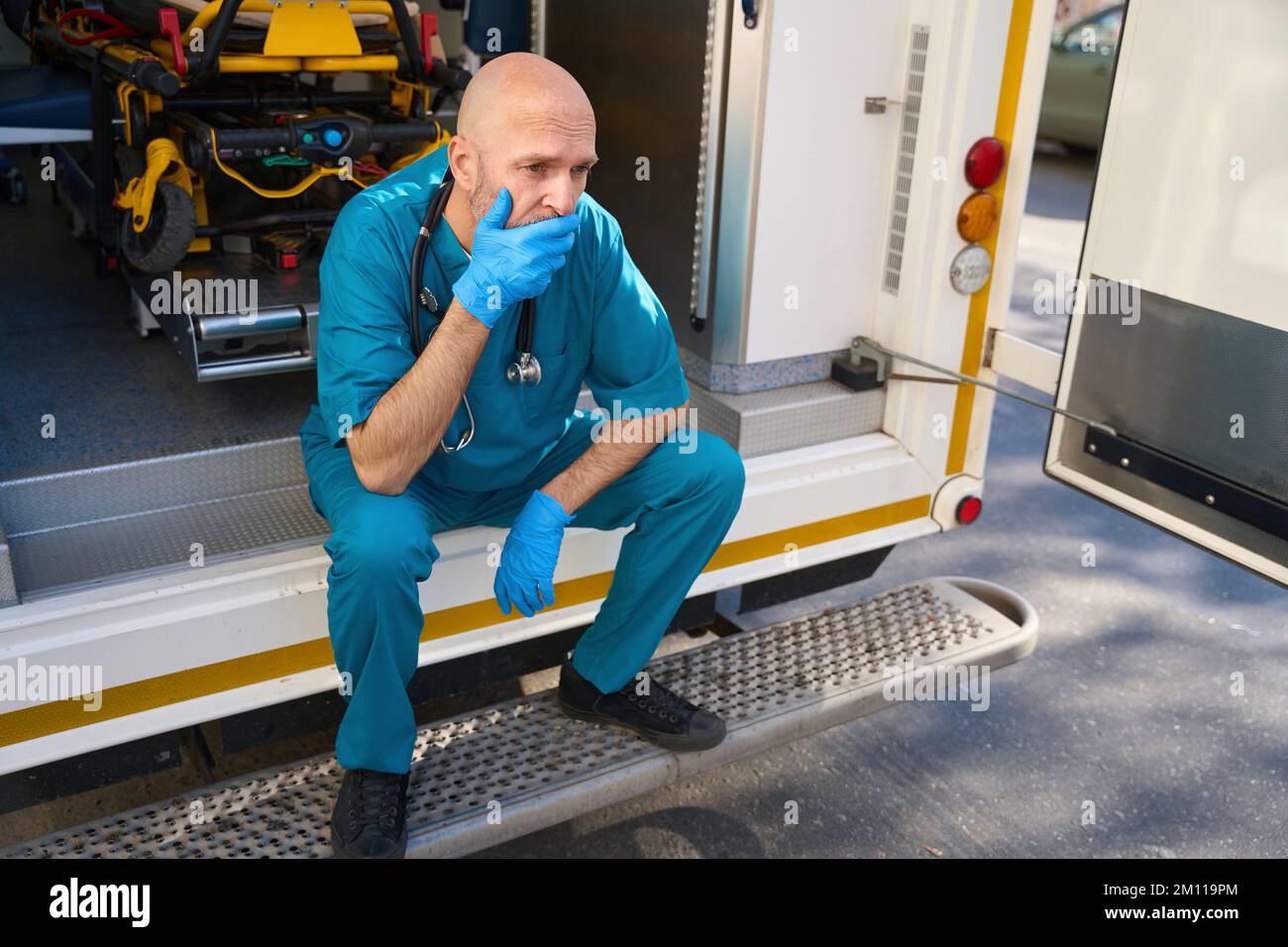 Doctor sits on the edge of ambulance and touches face Stock Photo - Alamy