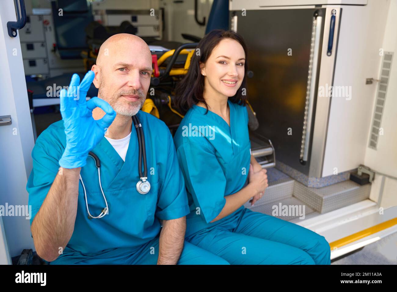 Ambulance crew of two people sit on foot ramp of service vehicle Stock ...