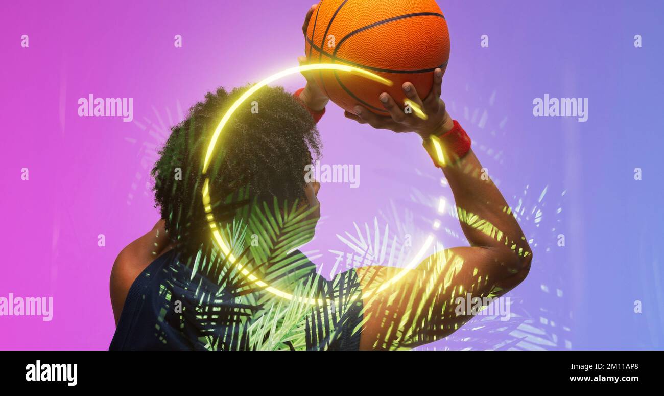 Rear view of biracial basketball player throwing ball by illuminated ...