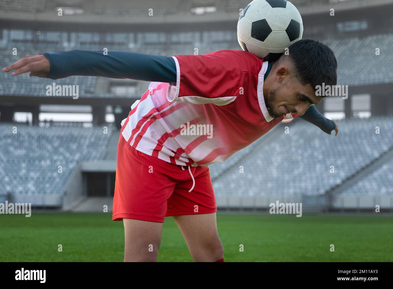 Biracial young soccer player balancing ball on back while practicing in ...