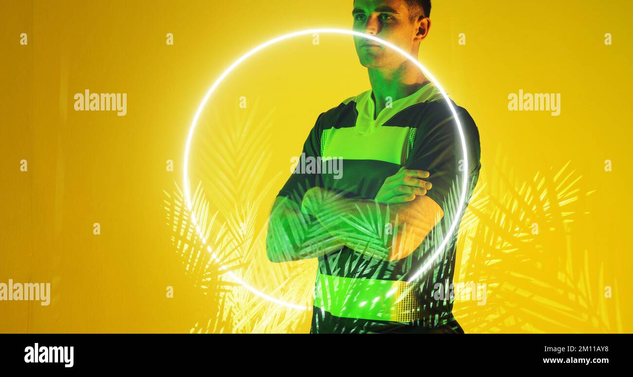 Caucasian rugby player with arms crossed by illuminated circle and ...