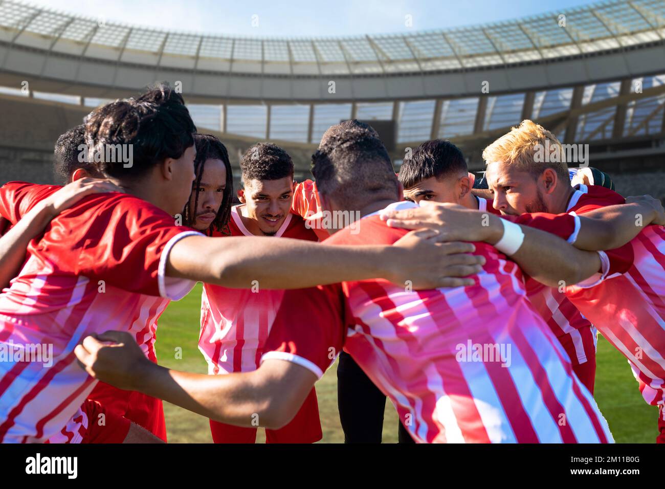Team of multiracial male players huddling and planning match strategy ...