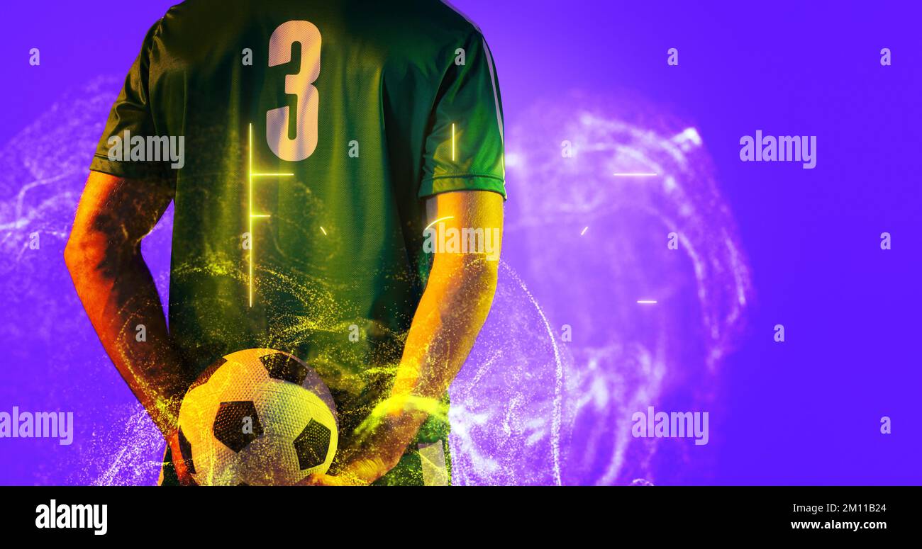 Rear view of soccer player holding ball with abstract neon in blue ...