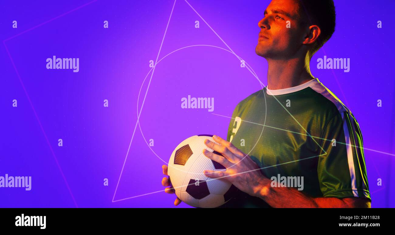 Caucasian young soccer player holding ball by geometric neon design ...