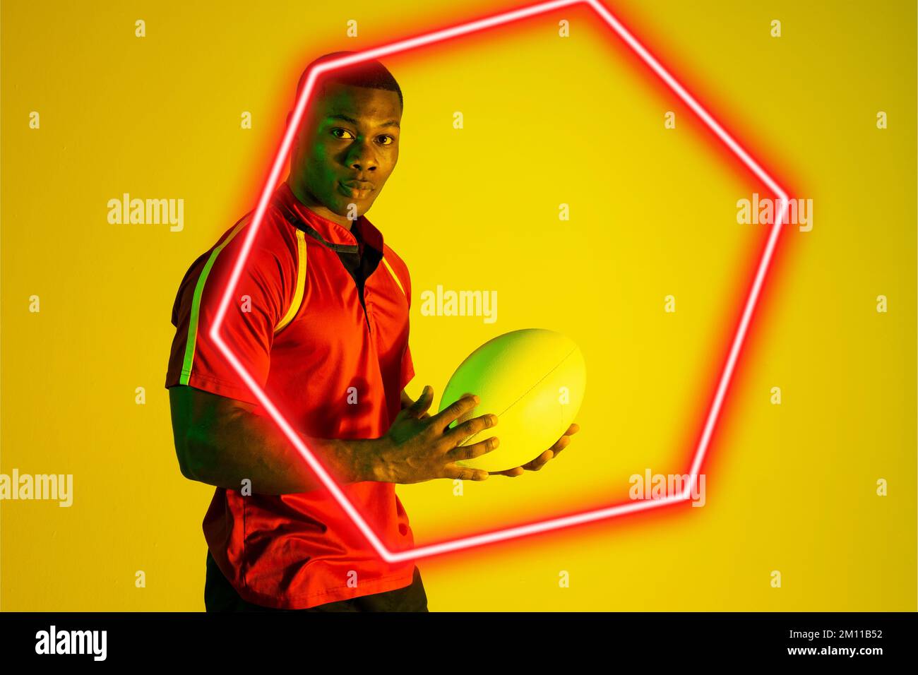 Hexagon neon over confident african american young rugby player holding ...