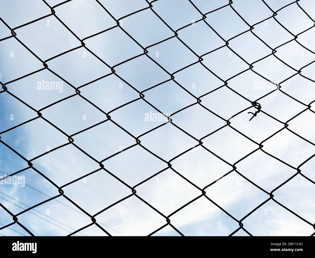 metal mesh fence. Grid net fencing wire against cloudy sky. selective ...