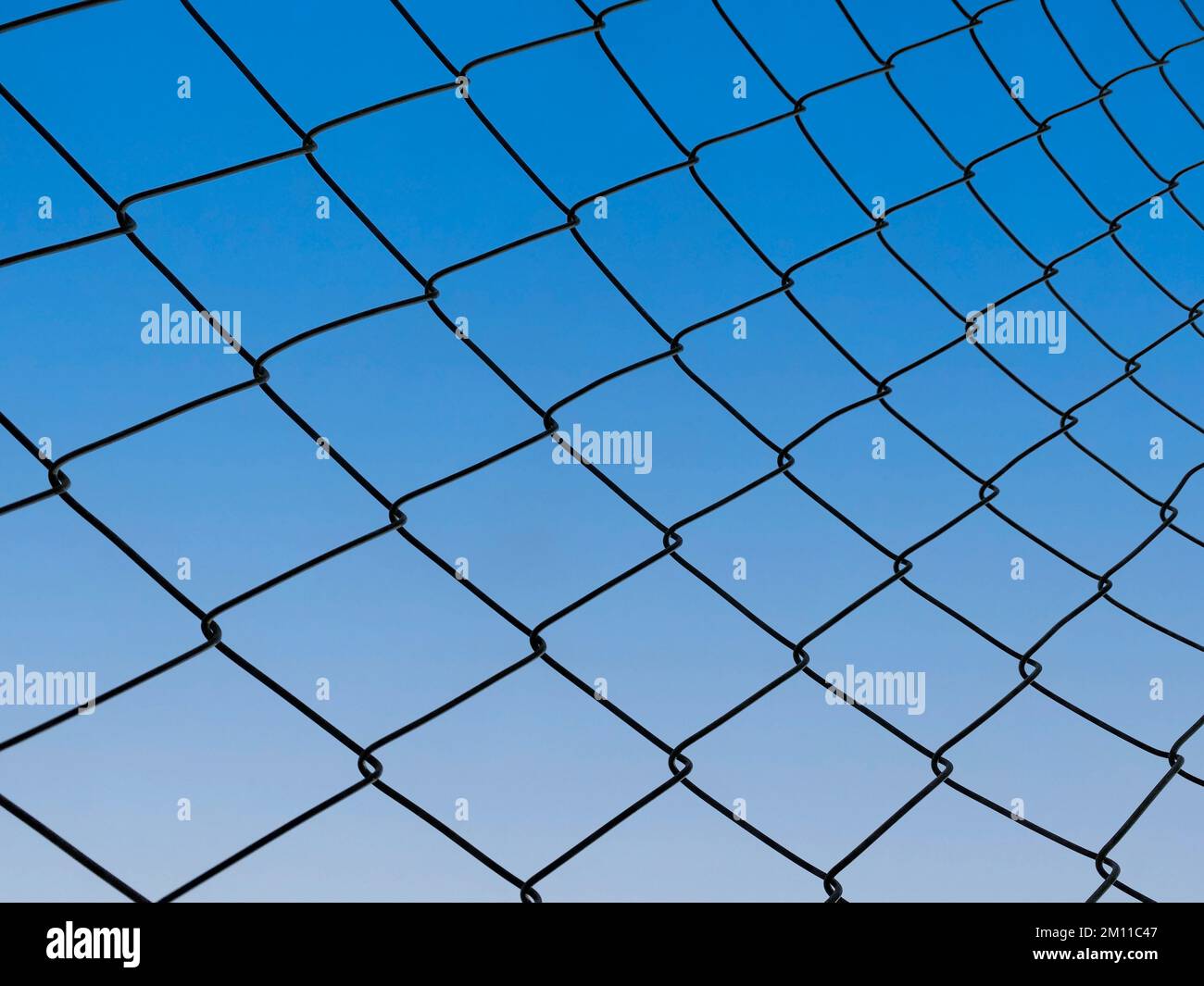 metal mesh fence. Grid net fencing wire against clear sky. selective ...