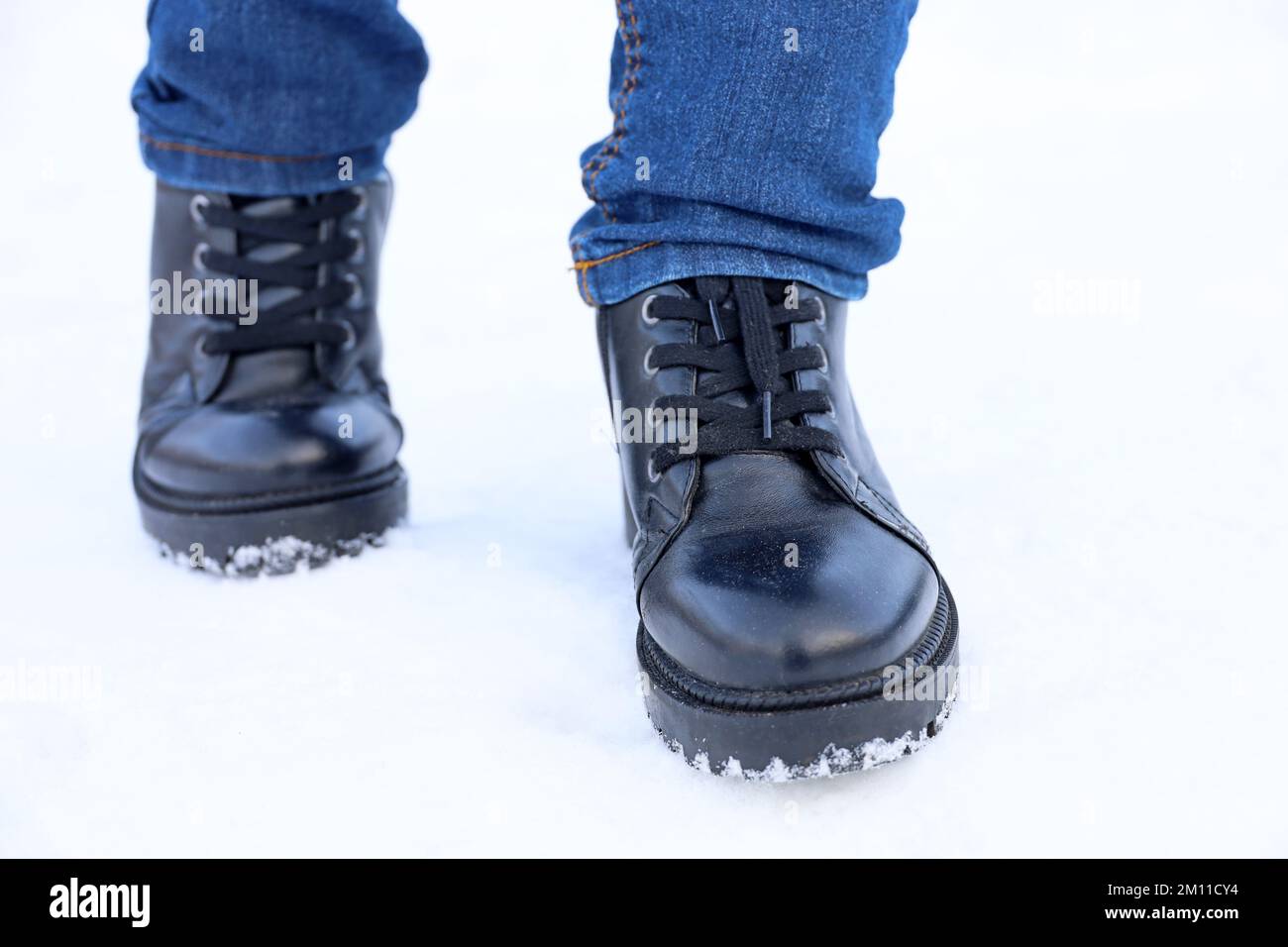 Female legs in black leather lace-up boots and jeans on a snow. Woman ...