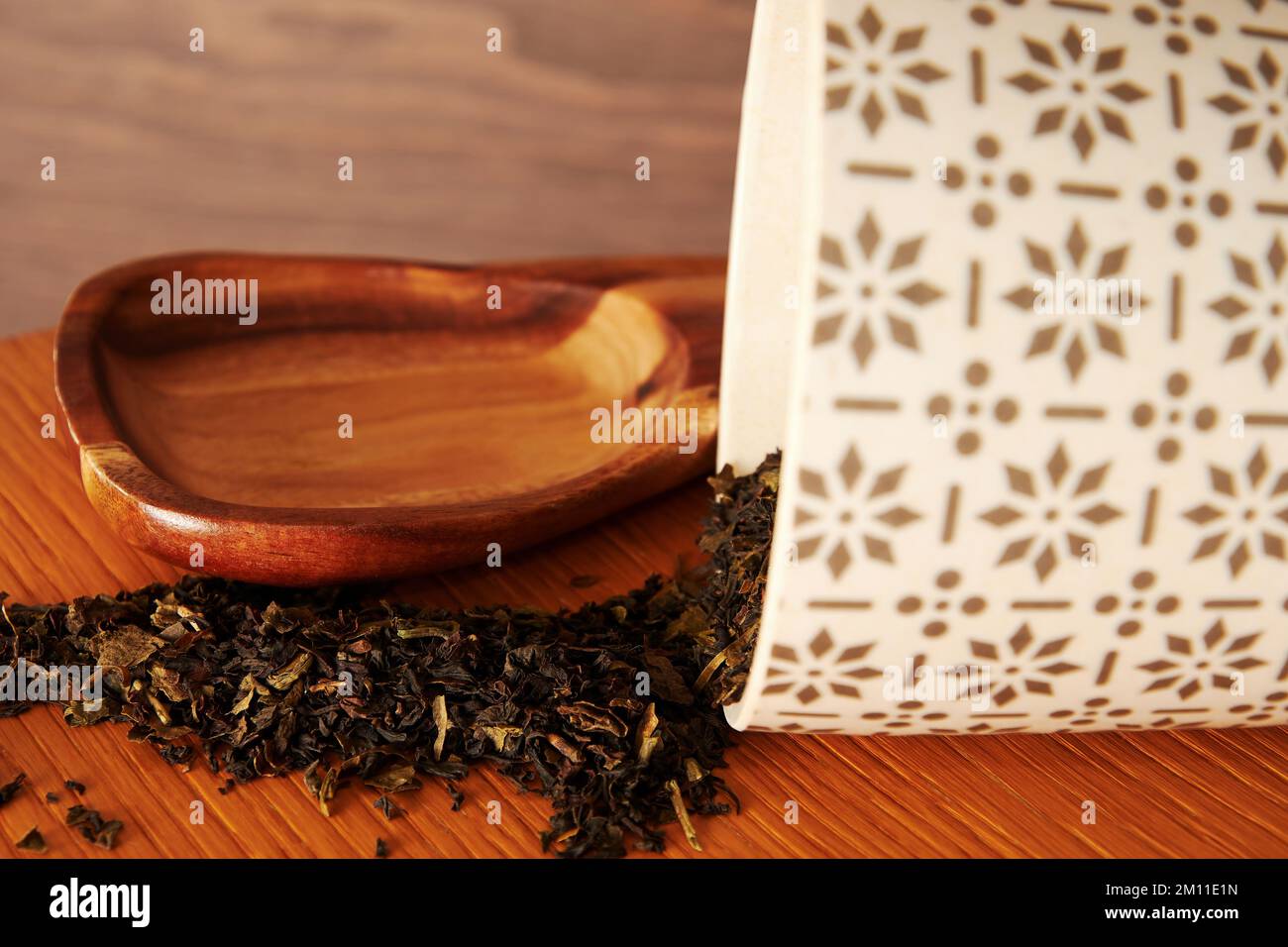 Black dry tea grain scattered from container on the kitchen table. Food ...