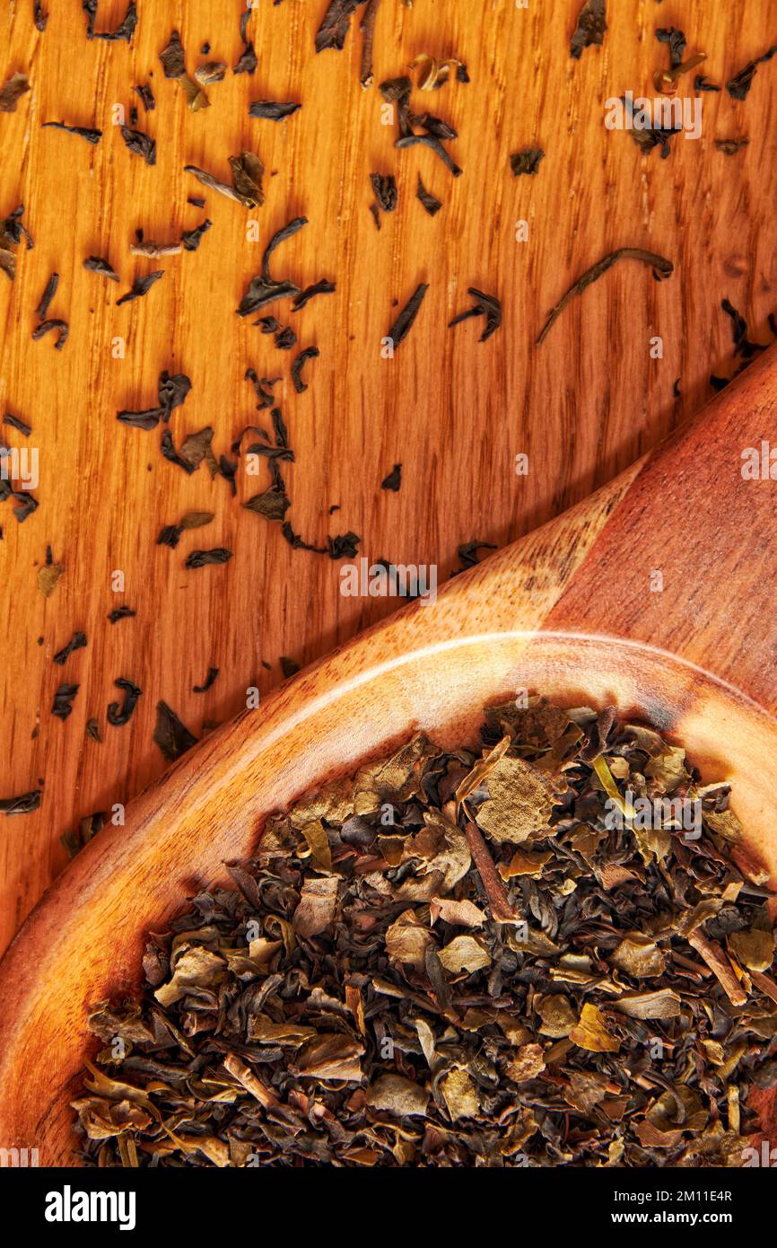 Flat lay template with black tea leaves and wooden spoon on the table ...