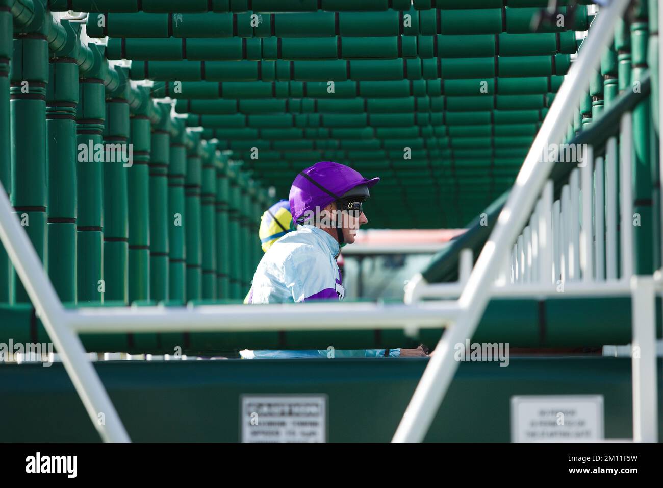 Jockeys seen through the side of the starting gates getting ready to ...
