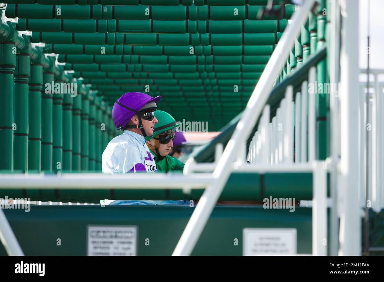 Jockeys seen through the side of the starting gates getting ready to ...