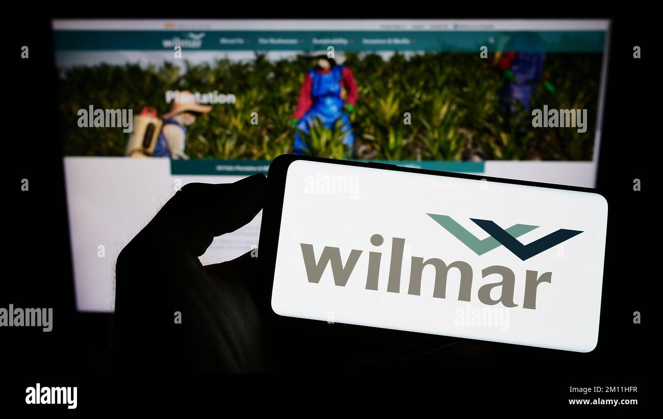 Person holding cellphone with logo of Singaporean company Wilmar ...