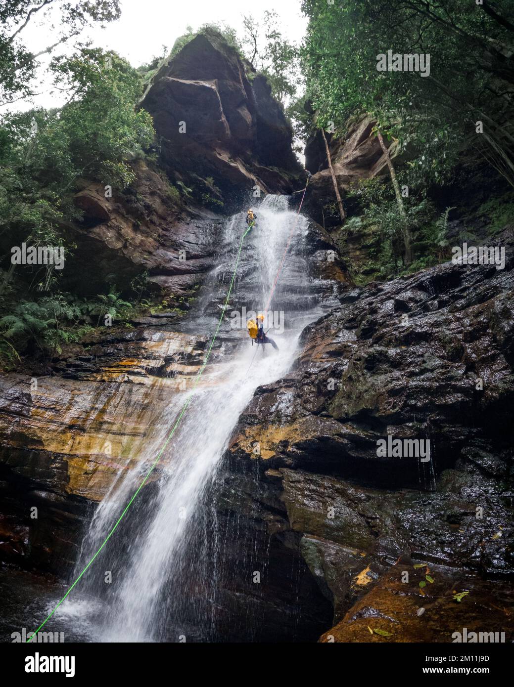 A few adventurers abseiling a waterfall cliff Stock Photo - Alamy