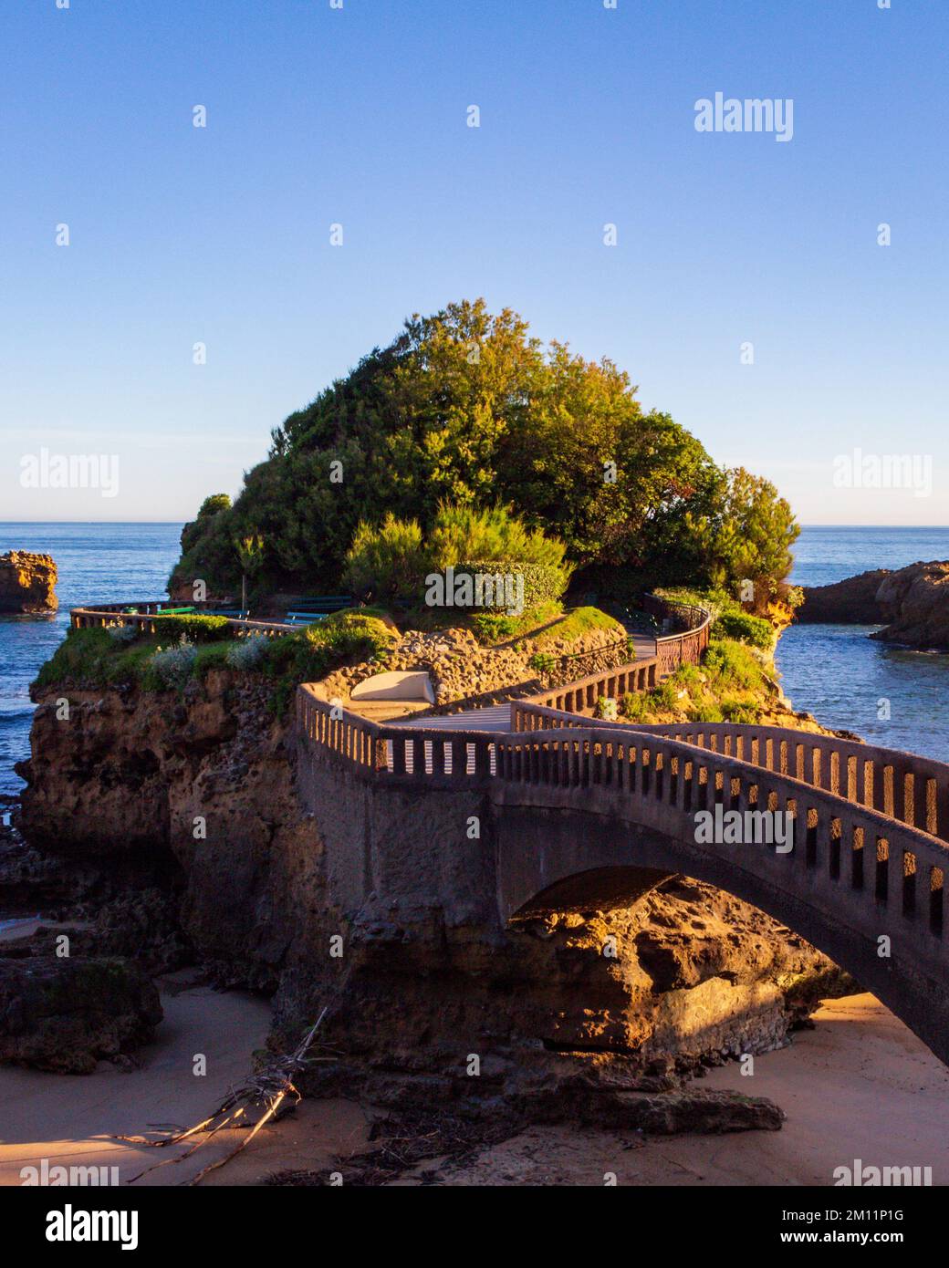 A vertical shot of a beautiful bridge on a cliff covered in green ...