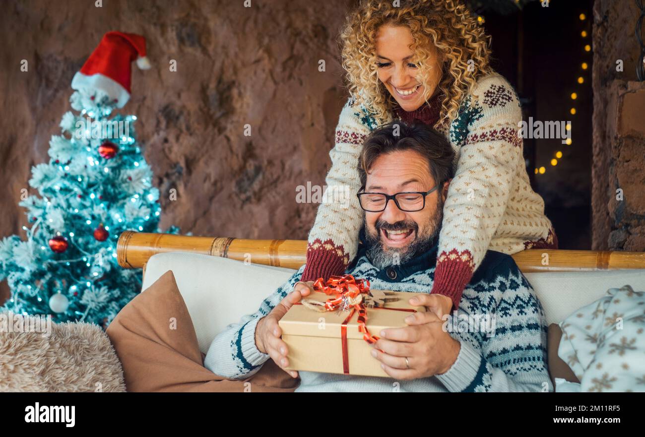 Christmas gift exchange moment at home with happy woman giving a man ...