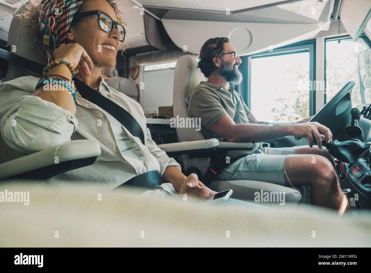 Side view of happy traveler couple inside camper van rv vehicle driving ...