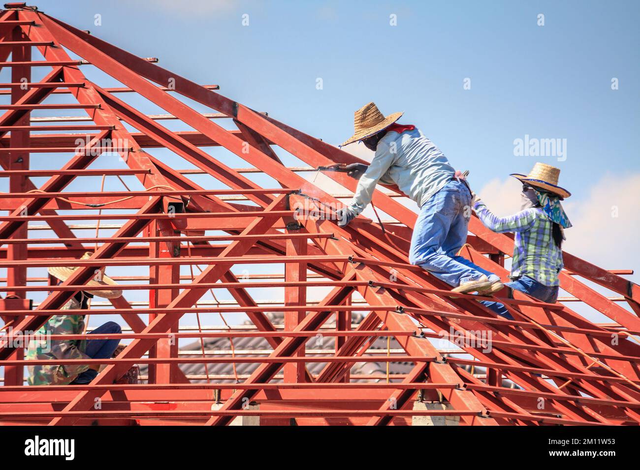 Construction welder workers installing steel frame structure of the house roof at building ...