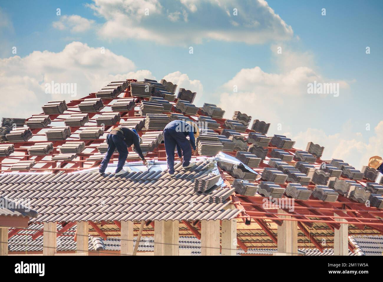 House construction. Roofers laying tiles on the roof of new building ...
