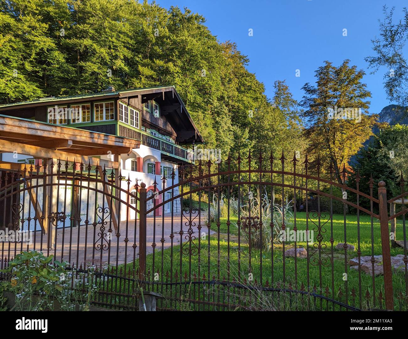 A rusty ornate fence with spikes in front of a typical Bavarian alpine ...