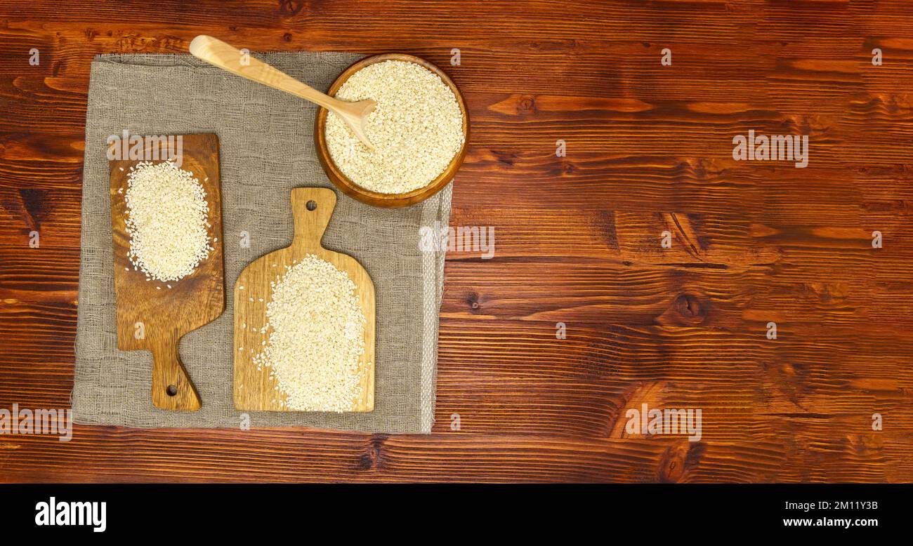 White sesame seeds in wooden bowl. Organic benne grains for healthy ...