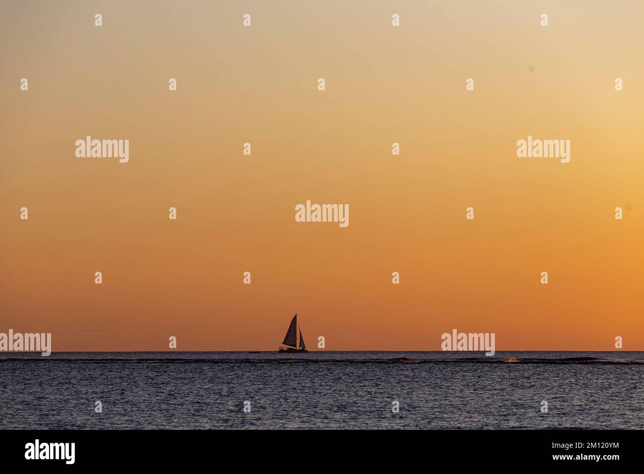 A lonely saling ship at the horizon during sunset at Mauritius Island ...