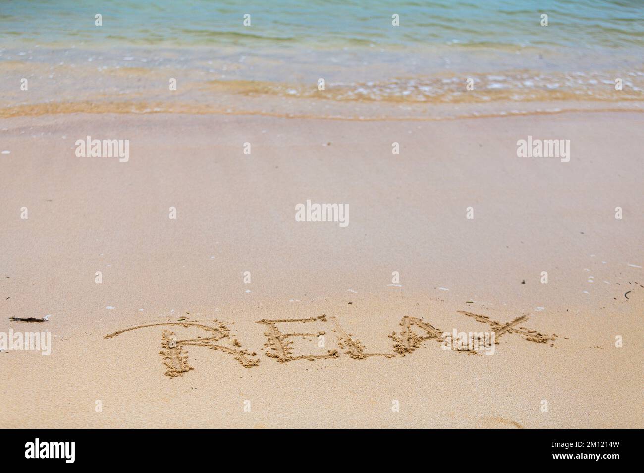 Relax - as a message written with a finger in the sand on a beach with ...