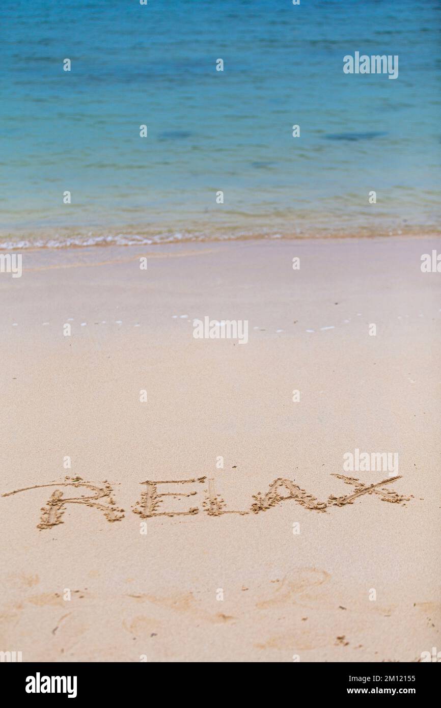 Relax - as a message written with a finger in the sand on a beach with ...