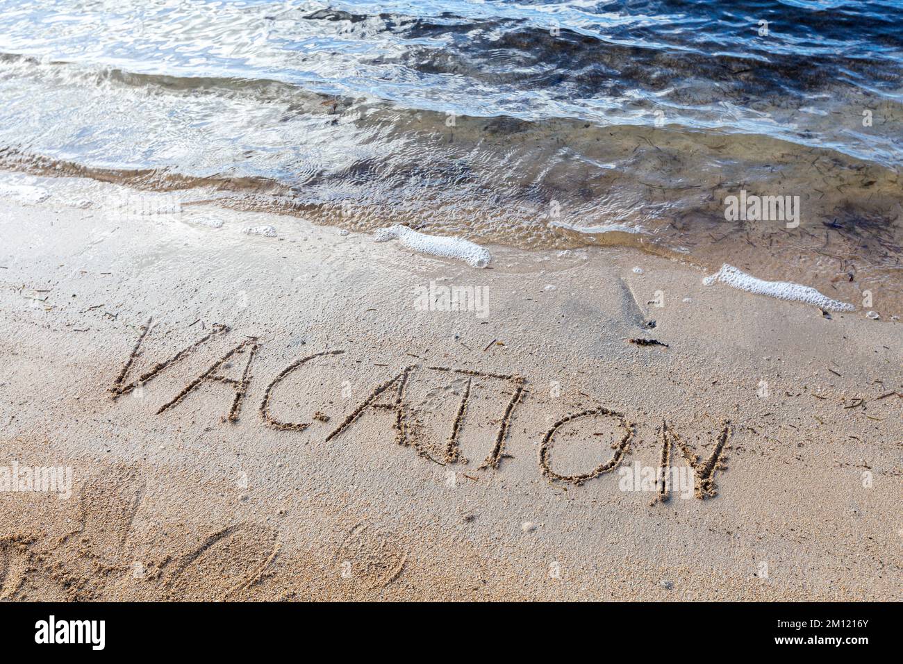 vacation - as a message written with a finger in the sand on a beach ...