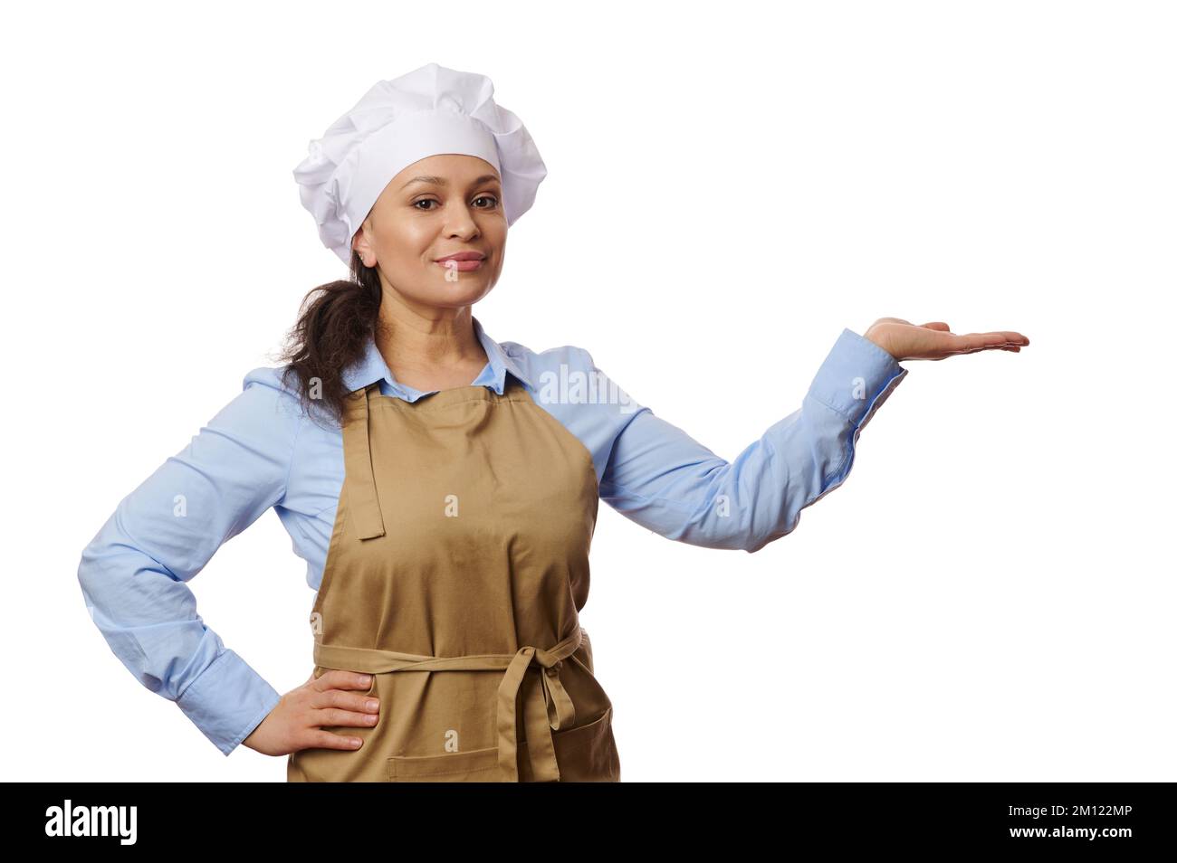 Pretty woman pastry chef in beige apron, holding copy space on her hand ...