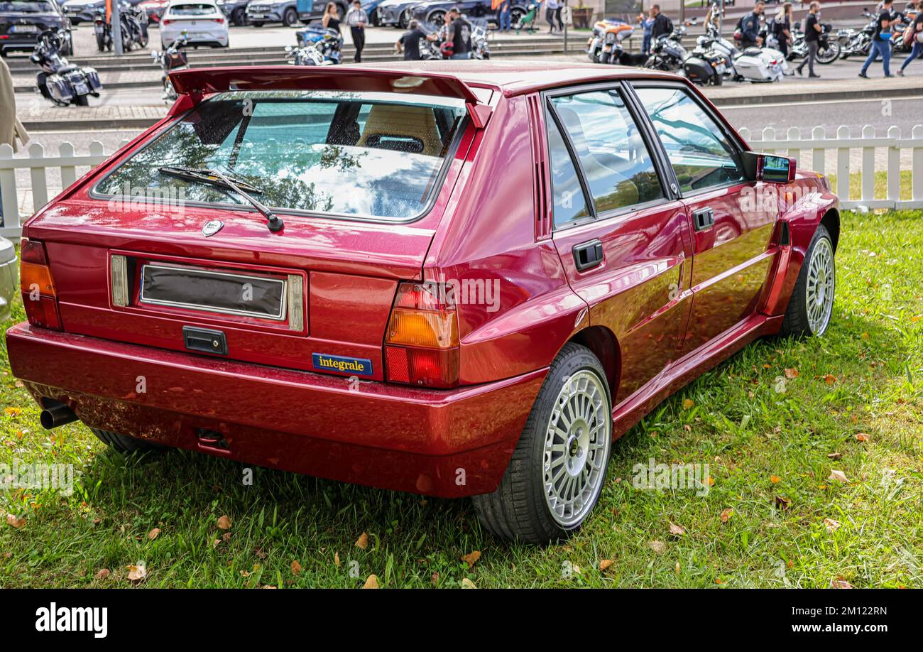 The view from behind of a red Lancia model Delta HF parked on the grass ...