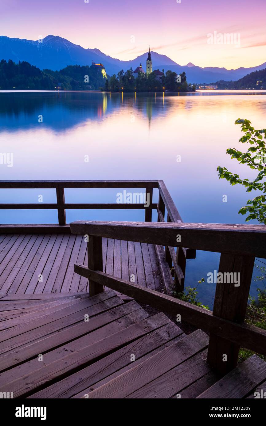 View of the wooden walkway around lake Bled at dawn in spring with the ...
