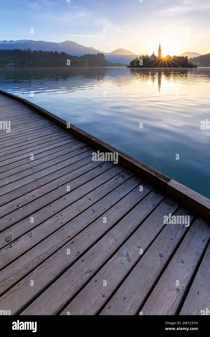 View of the wooden walkway around lake Bled at dawn in spring with the ...