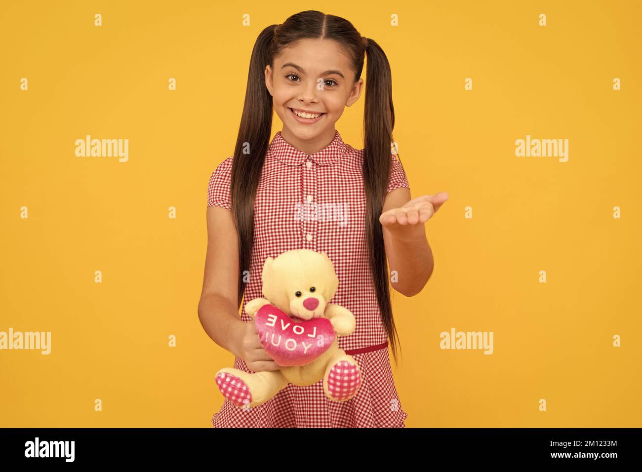 happy child presenting bear toy gift on yellow background, birthday ...