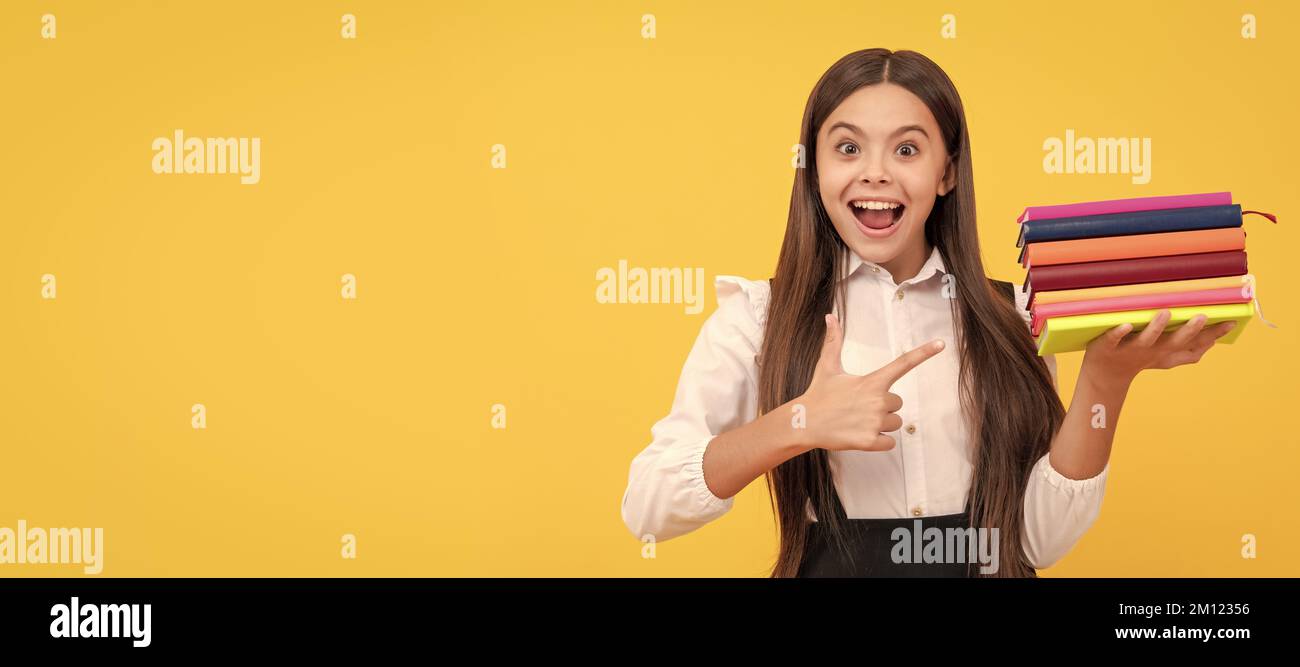 surprised teen girl in school uniform pointing finger on book stack ...