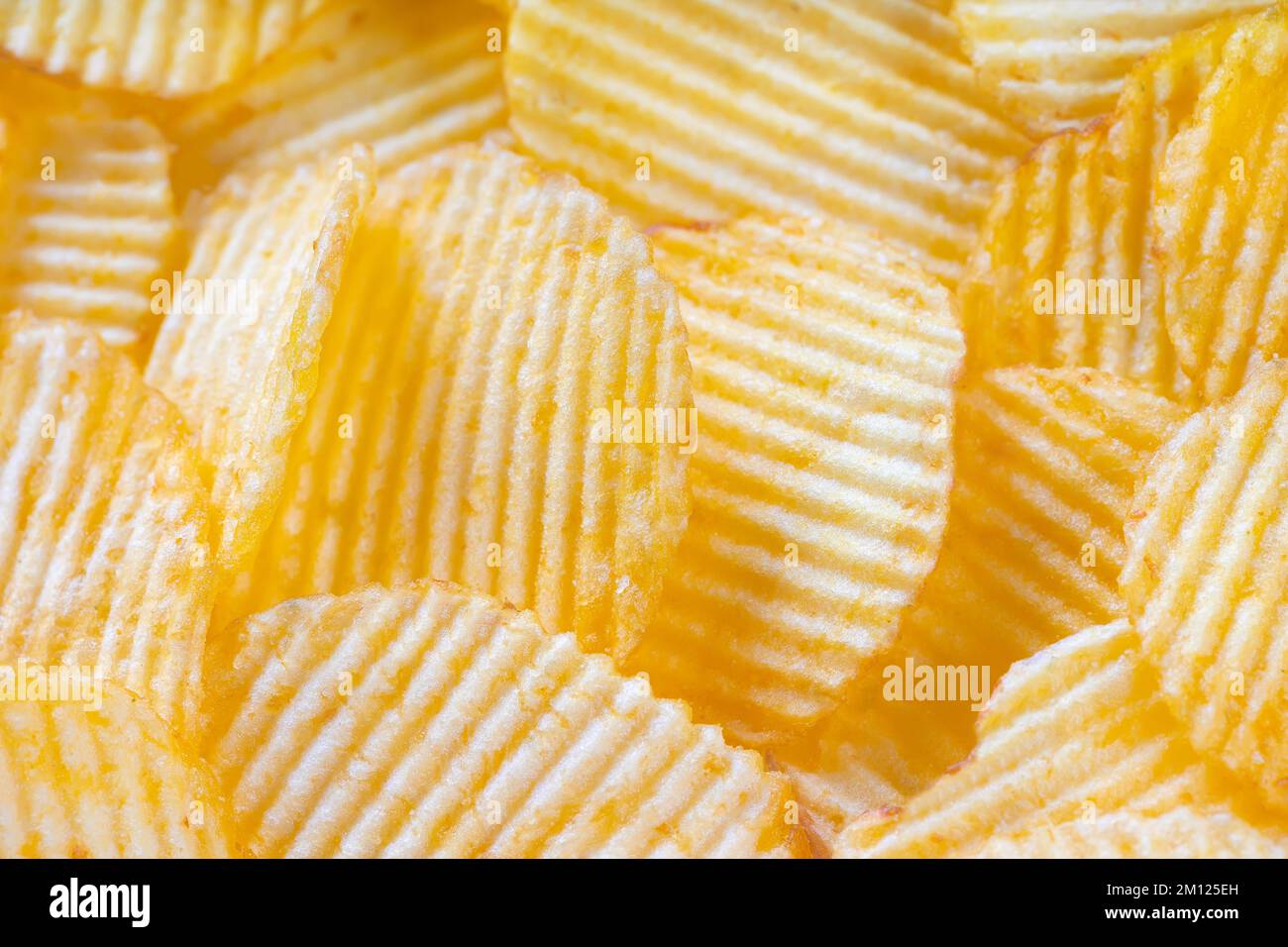 Yellow crispy ridged potato chips close up. Food background, banner ...