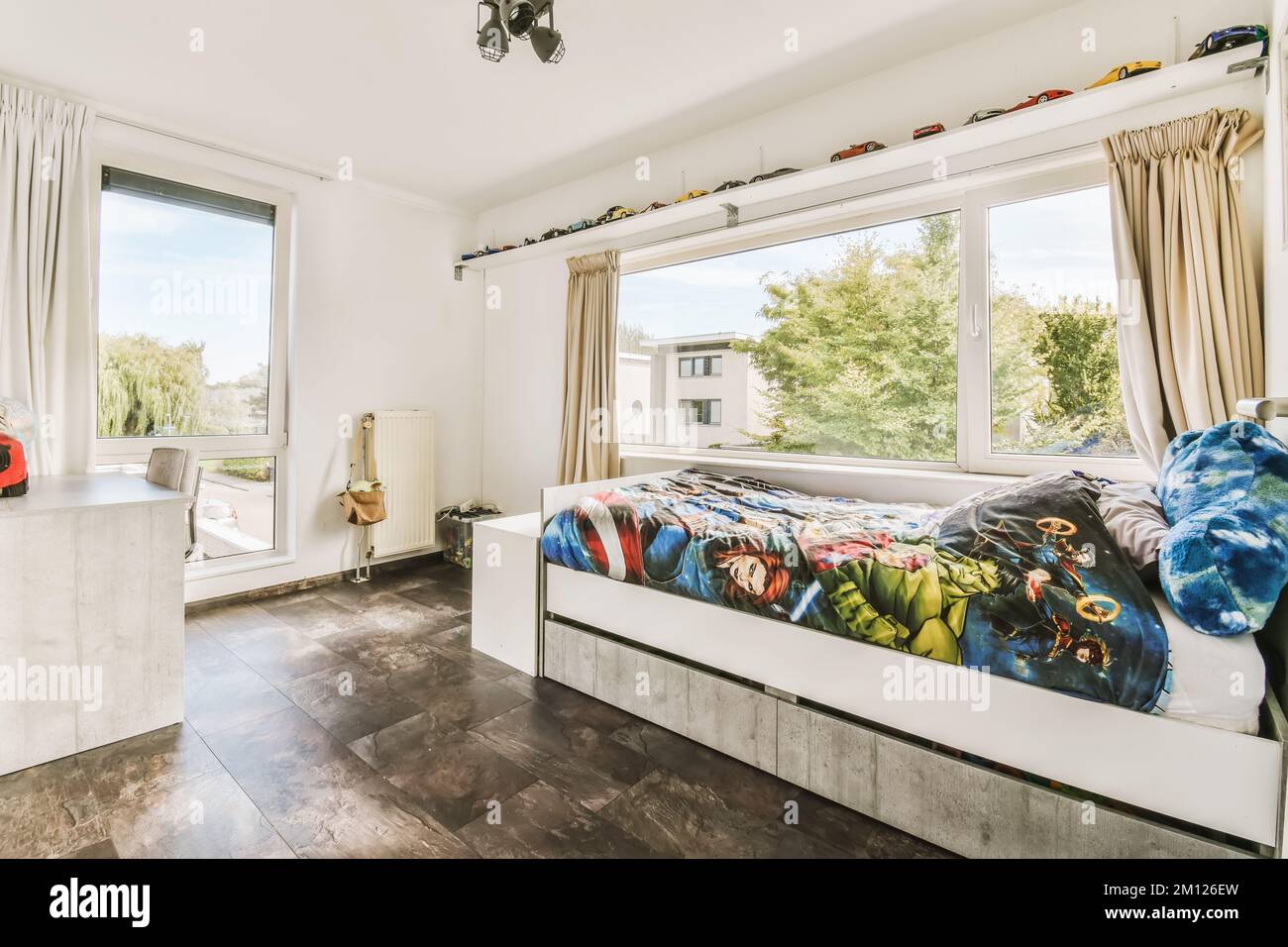 a kid's room with a bed, desk and window looking out onto the street in ...