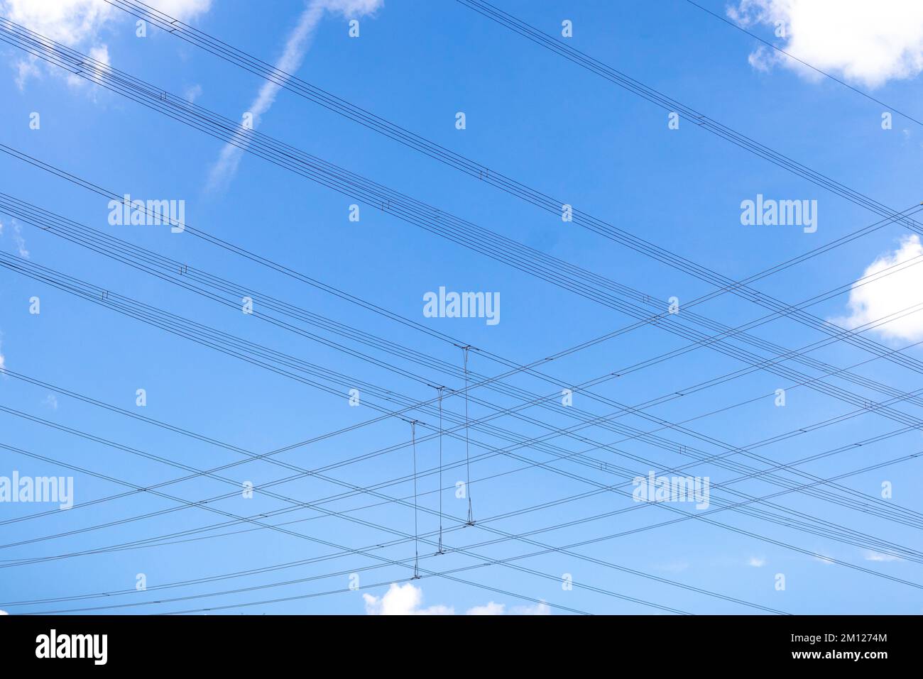 Power cables from overhead power lines against blue sky in Germany ...
