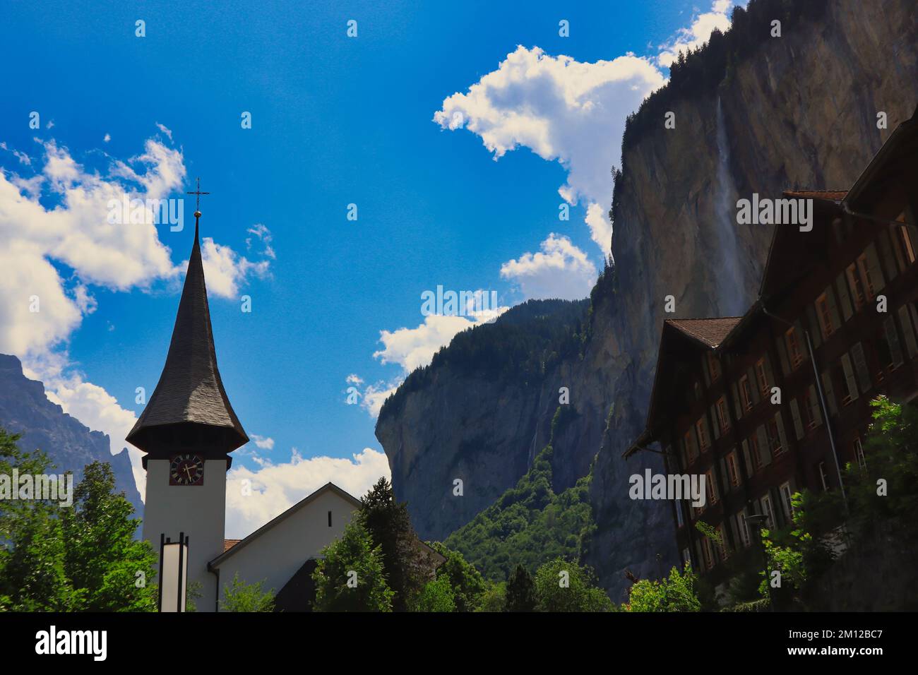A low angle shot of a church with tall rocky mountains in the ...