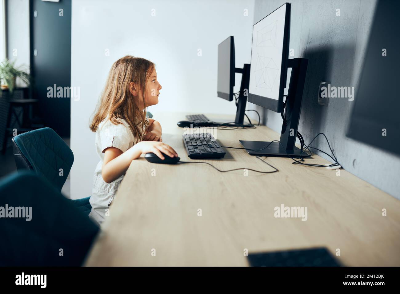 Engaged absorbed schoolgirl learning to use technology in classroom at ...