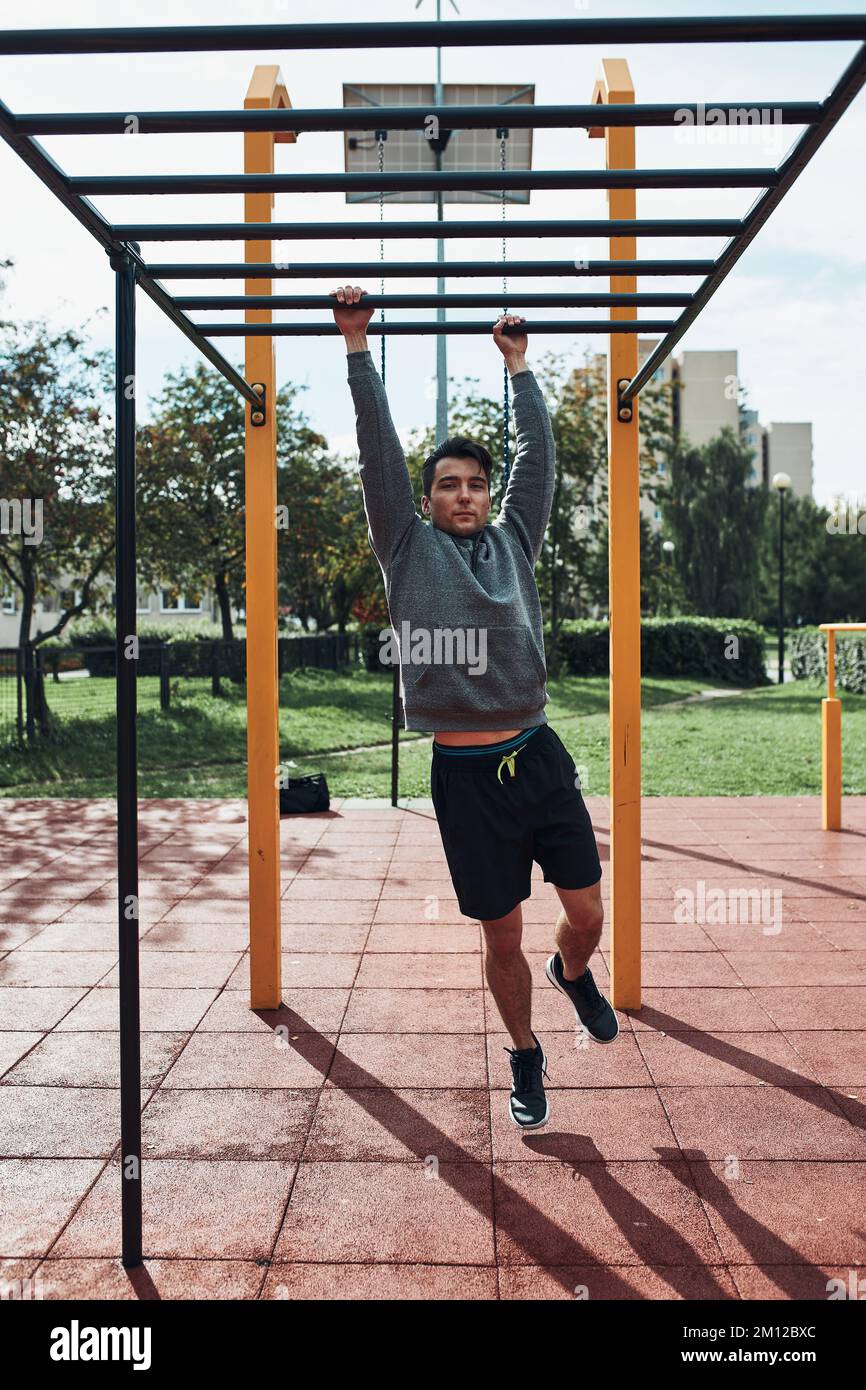Young man bodybuilder exercising on monkey bars during his workout in a ...