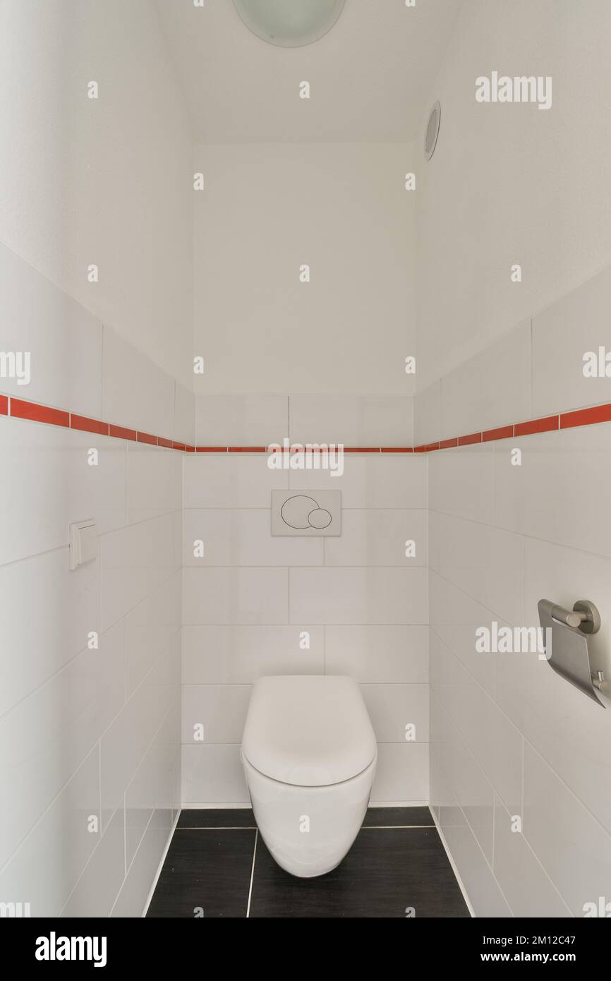 a white toilet in a bathroom with red and white tiles on the wall ...