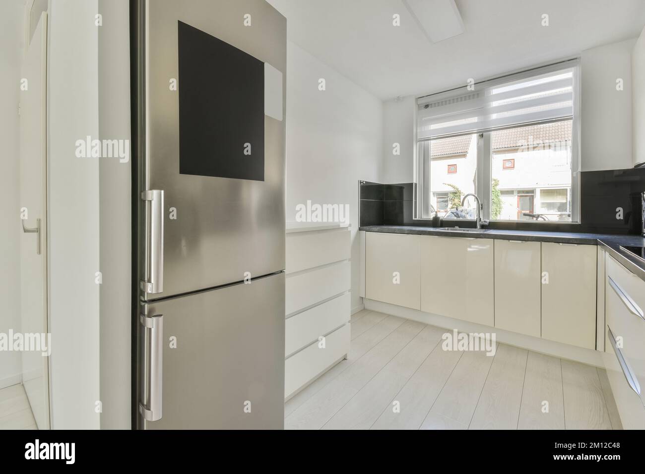 a modern kitchen with white cabinets and black counter tops on the ...