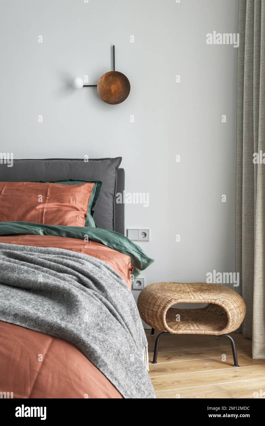 Bedroom interior with rust color linen and cushions on a bed, grey ...