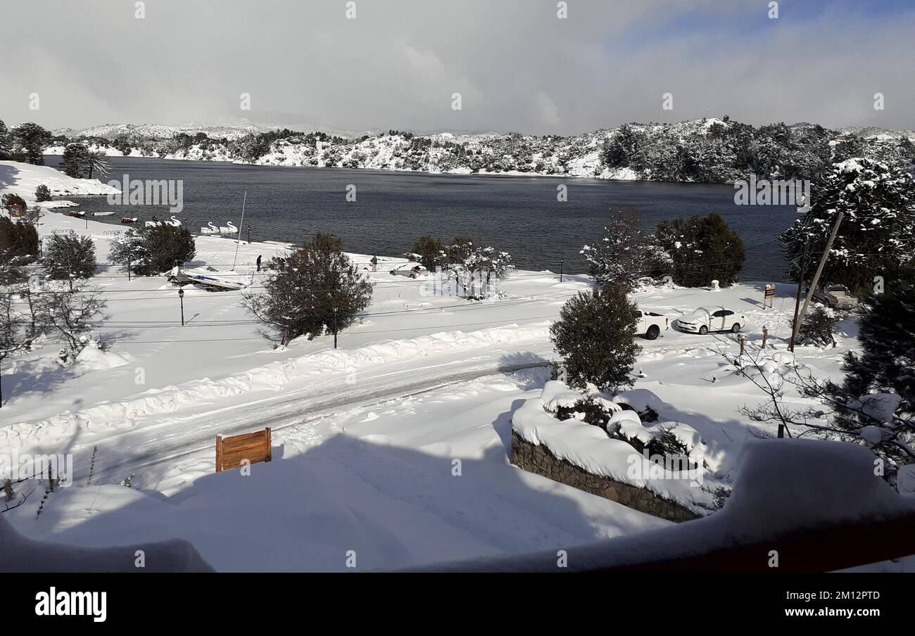 An aerial shot of a field covered with a snow with a river in the ...