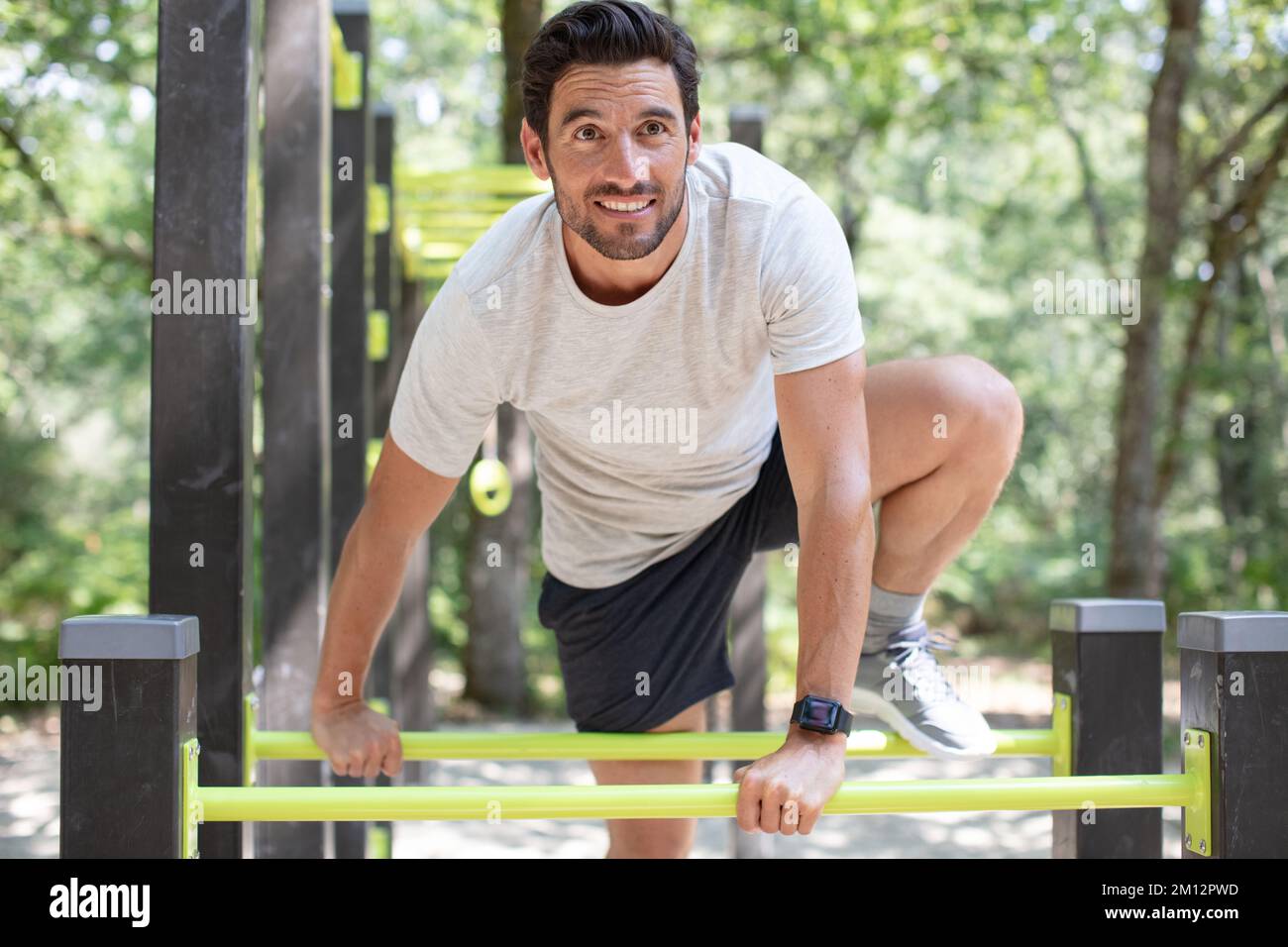muscular man jumping pull-ups on horizontal bar in park Stock Photo - Alamy