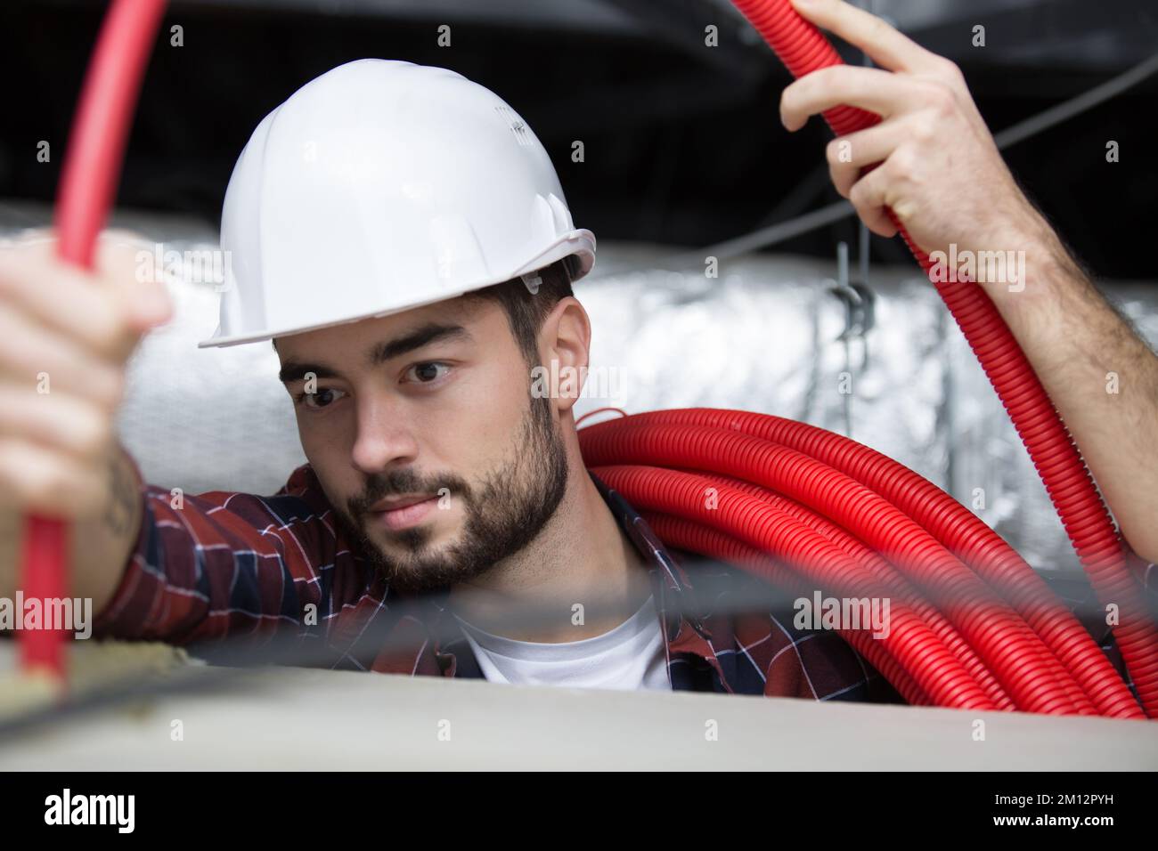 electrician is fixing an electric corrugated tube to the ceiling Stock ...